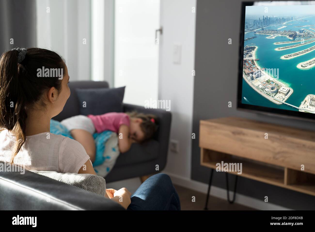 Woman Watching TV At Sofa While Child Is Sleeping Stock Photo - Alamy