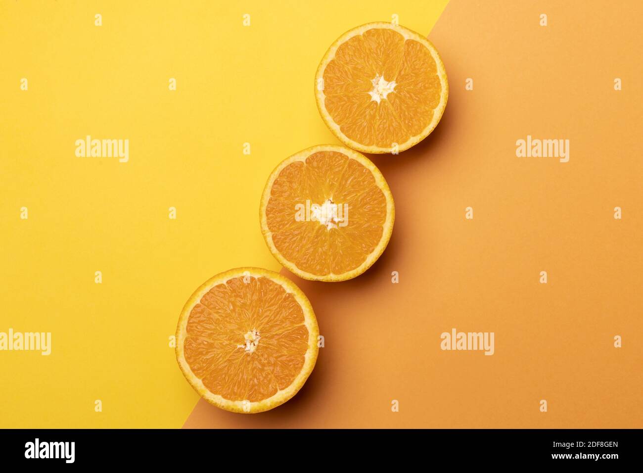 A high angle shot of slices of fresh orange on a yellow and orange ...