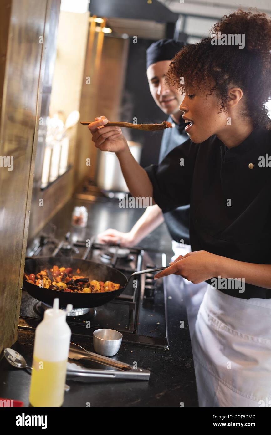 Female african american chef tasting food while cooking at restaurant ...