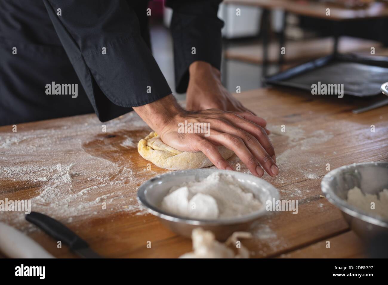 Mixed race male chef wearing black apron in kitchen Stock Photo - Alamy