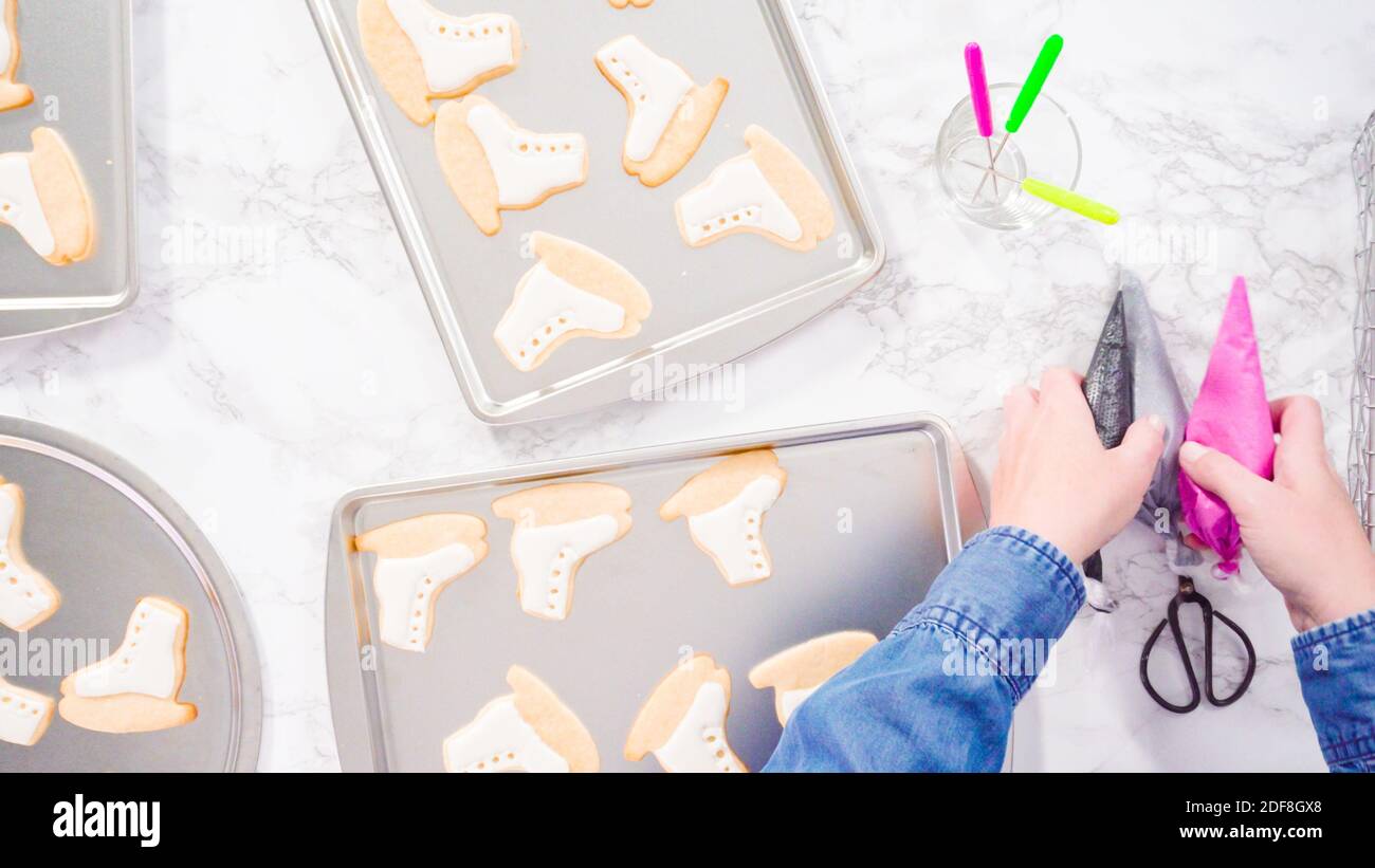 Flat lay. Decorating ice skate shaped sugar cookies with white color ...