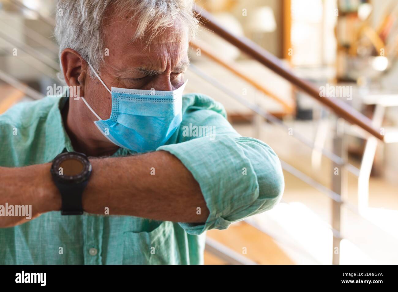 Senior caucasian man wearing face mask coughing into arm Stock Photo ...