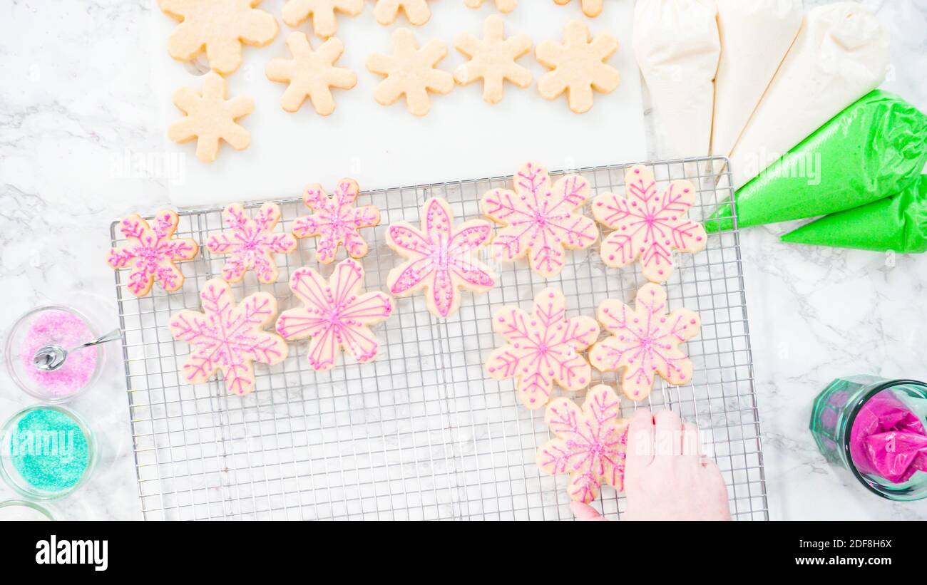 Flat lay. Stp by step. Icing snowflake shaped sugar cookies with pink ...