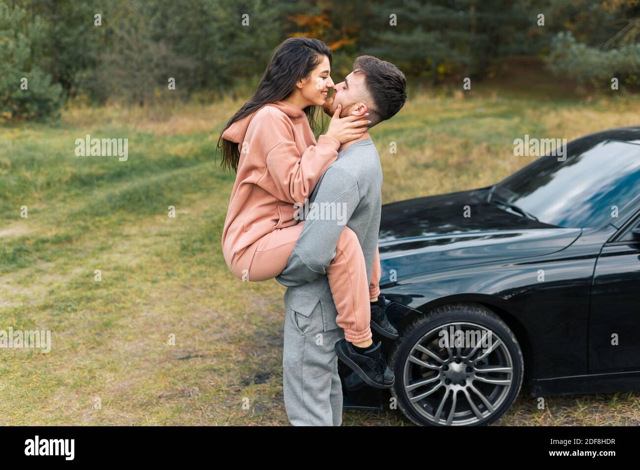 Beautiful young couple in tracksuits near their car. Happiness girl in ...
