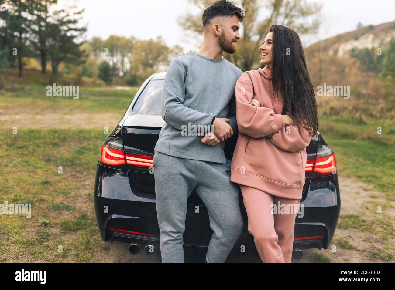 Beautiful couple talking and flirting leaning on their car Stock Photo ...