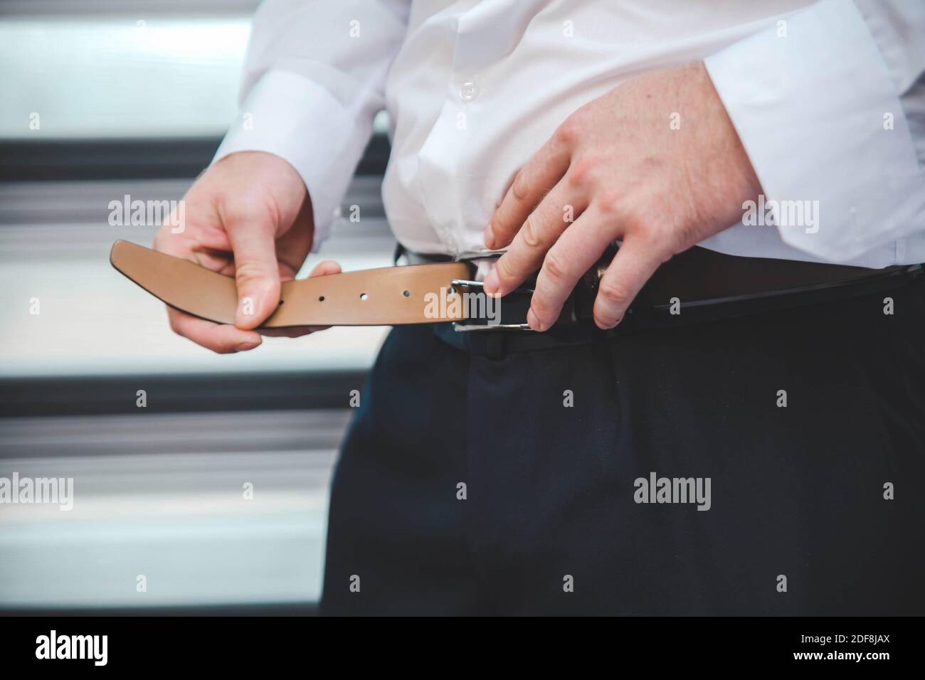 Grooms morning preparation, a man putting on a belt Stock Photo - Alamy