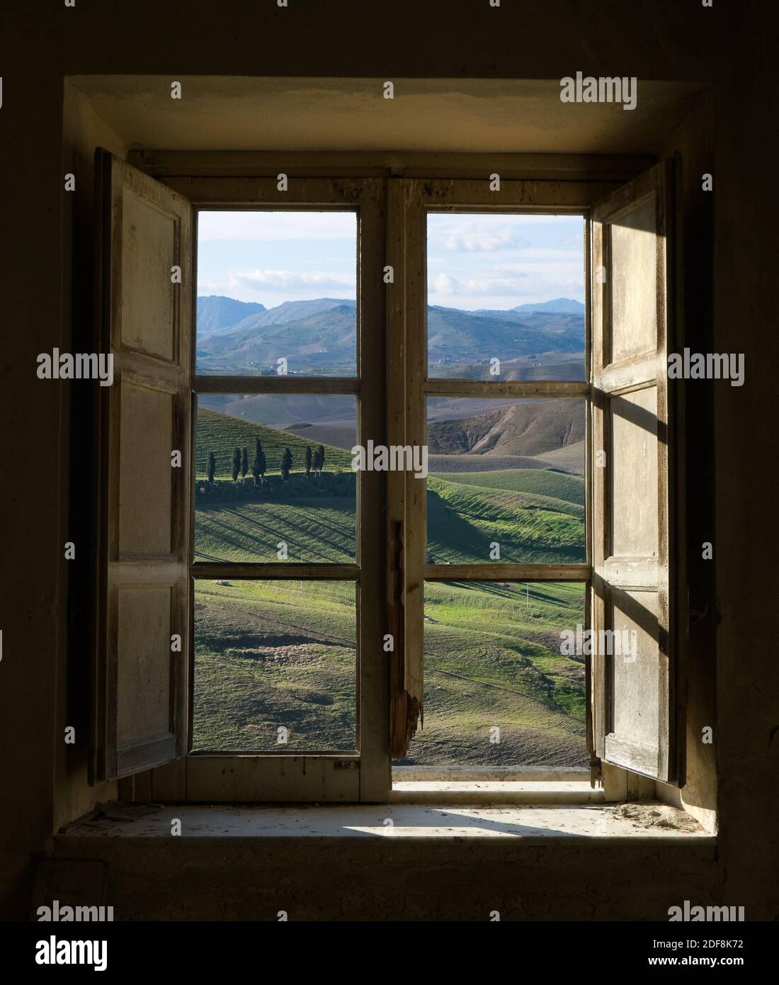 outside view of cypress trees and green hills through a shabby window ...