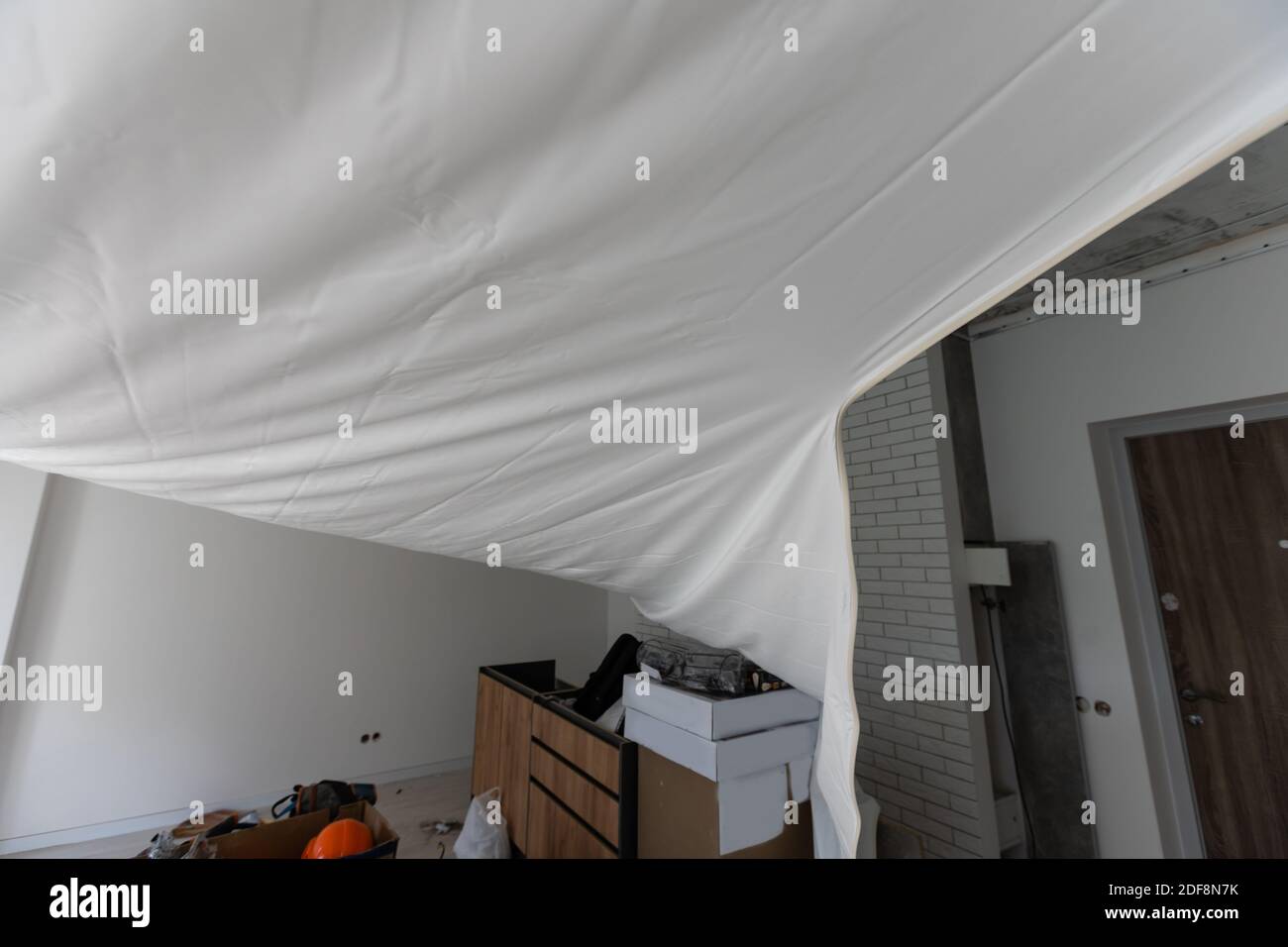 repairmen install stretch ceiling made of pvc vinyl film using a gas ...