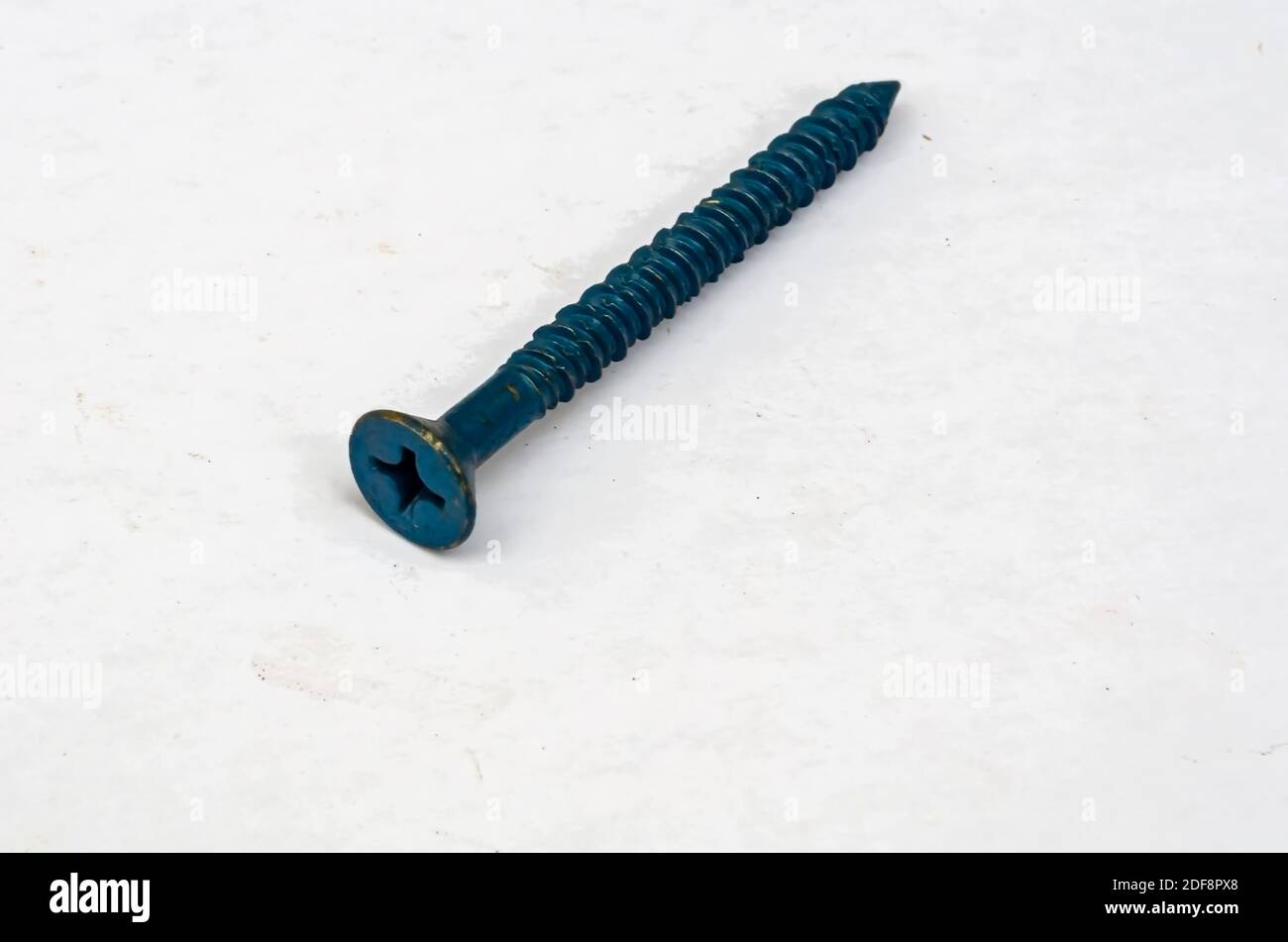 On a white background is a blue flat head screw with a cross slot for ...