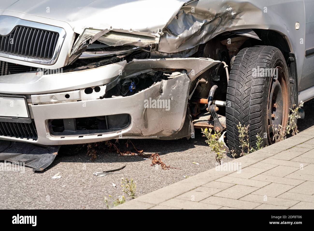 Crashed silver car wreck, detail on front bumper deformed metal plates ...
