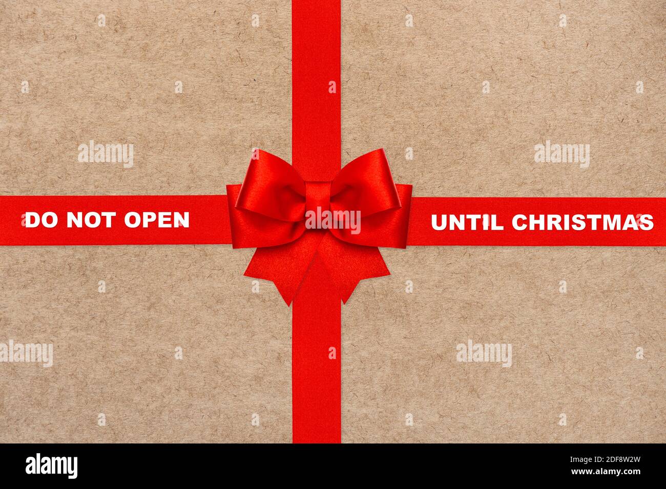 Christmas wrapping. Red ribbon bow on craft paper texture. DO NOT OPEN ...