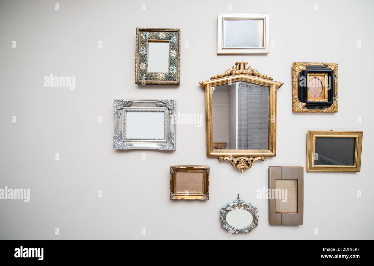 An eclectic mix of mirrors and picture frames on a white wall Stock ...