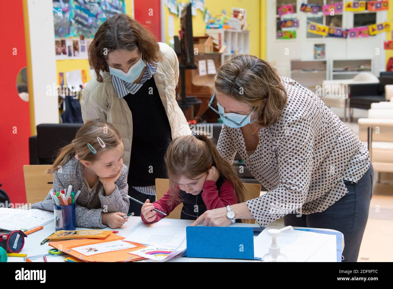 Teachers wear a protective facial mask with schoolchildren during a ...