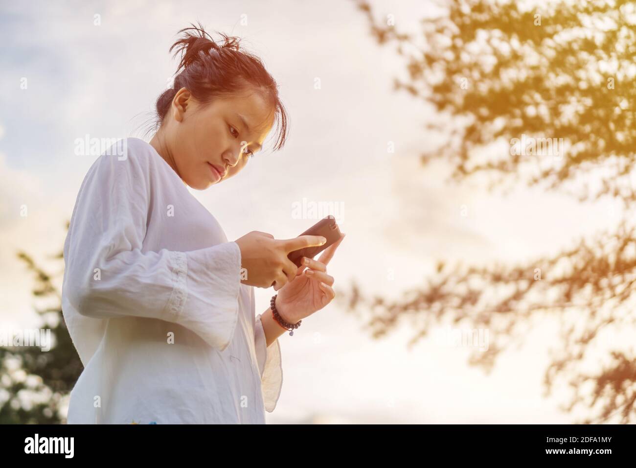 Concerned looking Asian teenage girl looking at her phone Stock Photo ...
