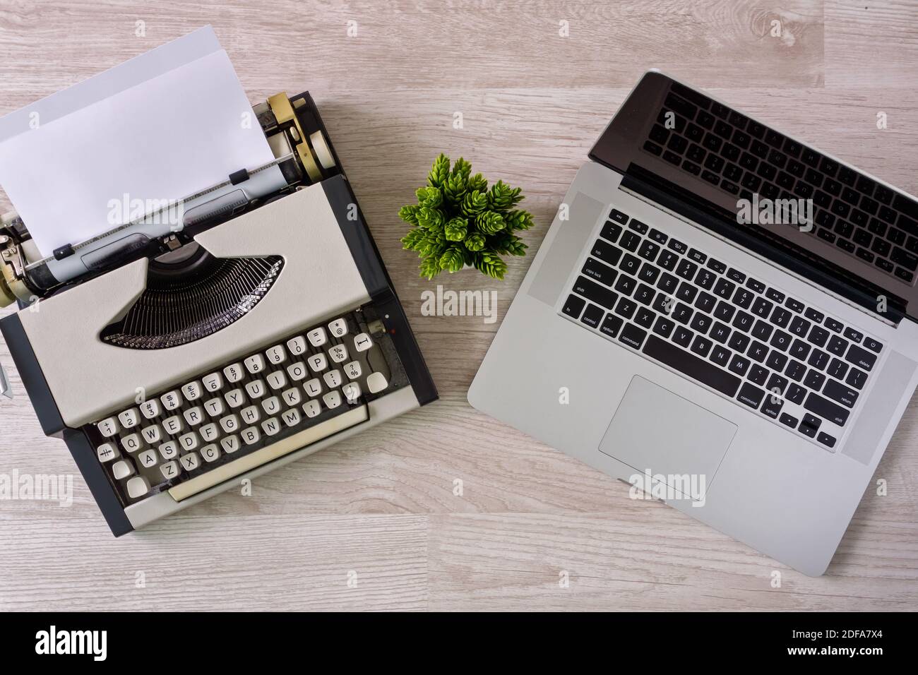 Overhead view of old typewriter with paper sheet and laptop side by ...