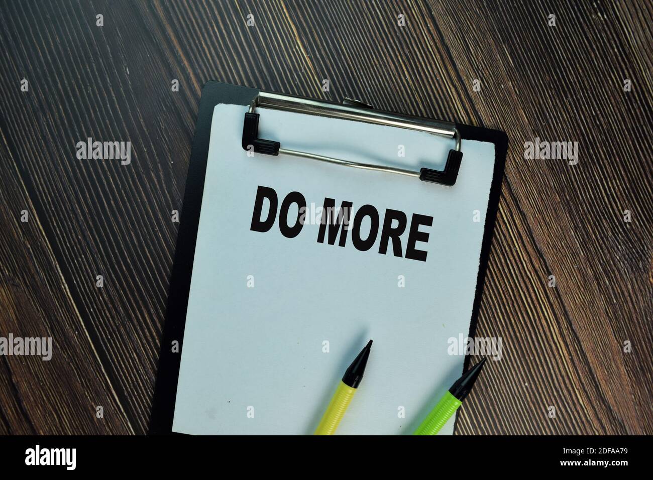 Do More write on a paperwork isolated on Wooden Table Stock Photo - Alamy