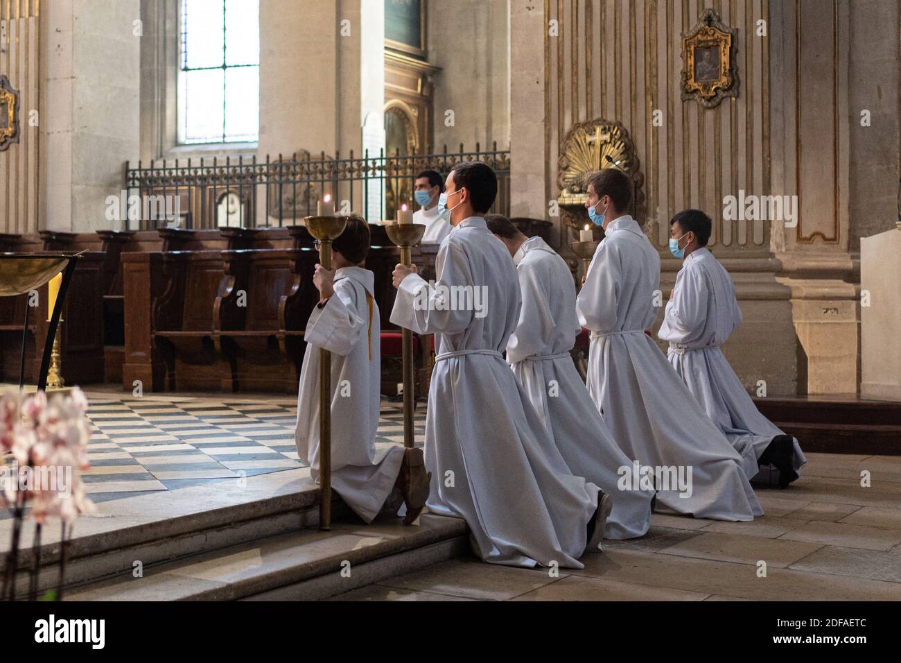 Altar servers kneel in front of the altar wearing protective masks ...