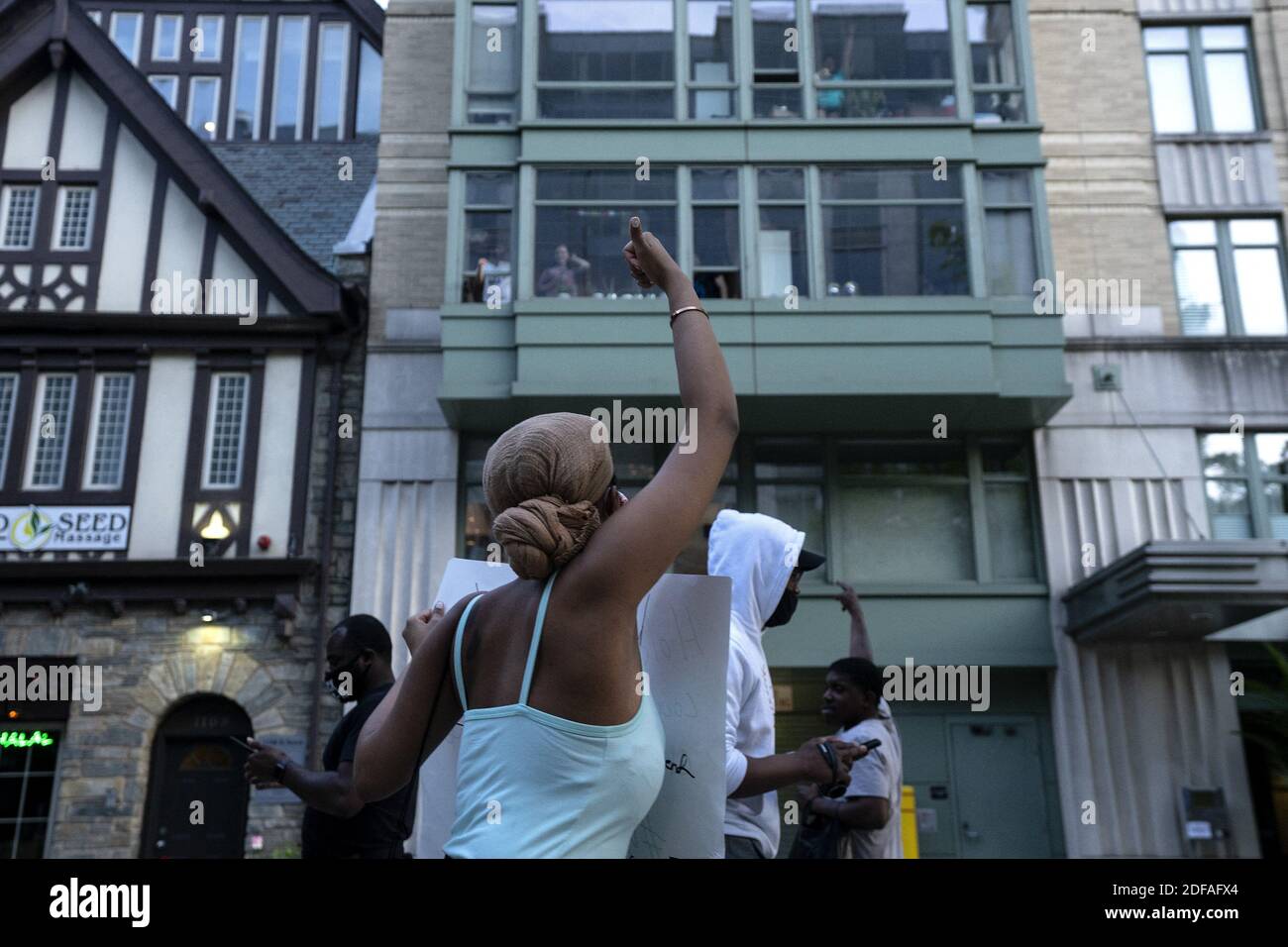 A protestor gives a thumbs up to supporters cheering from their window ...