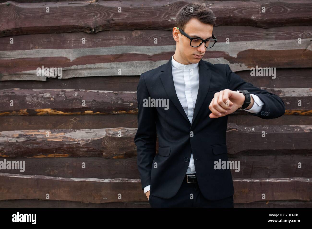 The guy looks at his watch. Boy reading book isolated on wooden ...