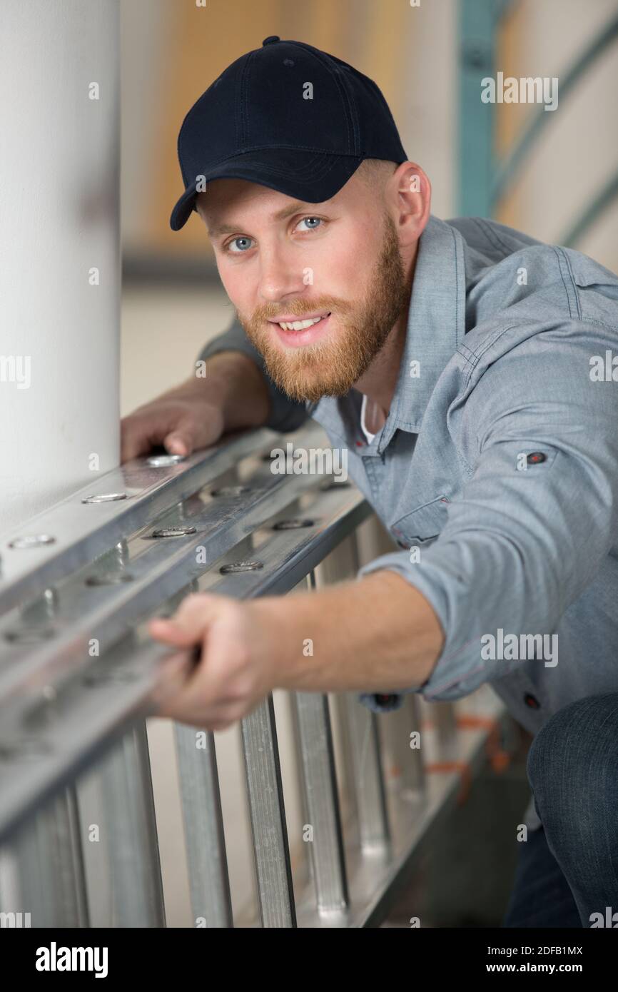 cheerful young man carrying ladder Stock Photo - Alamy