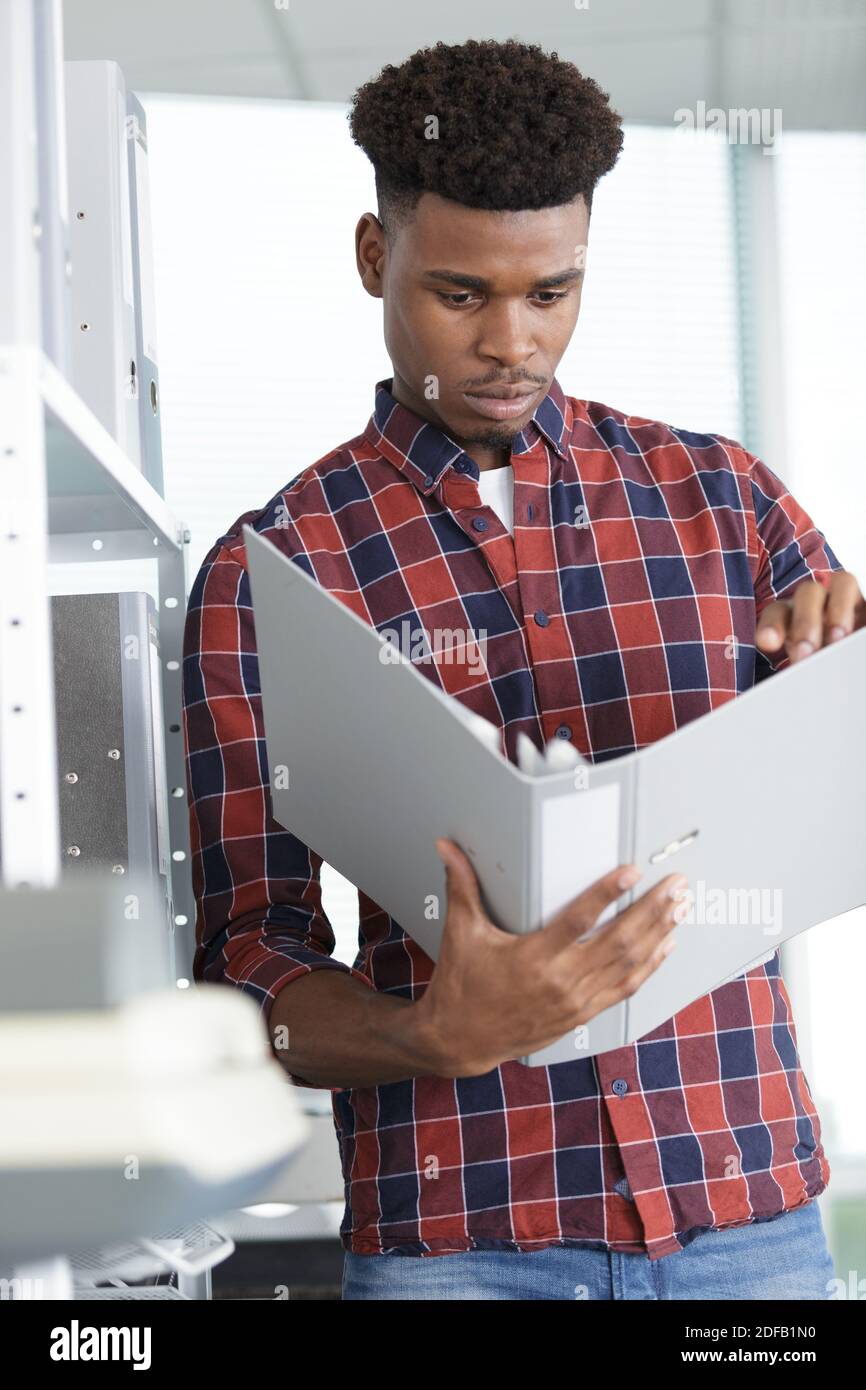 young businessman taking folder from shelf at workplace Stock Photo - Alamy
