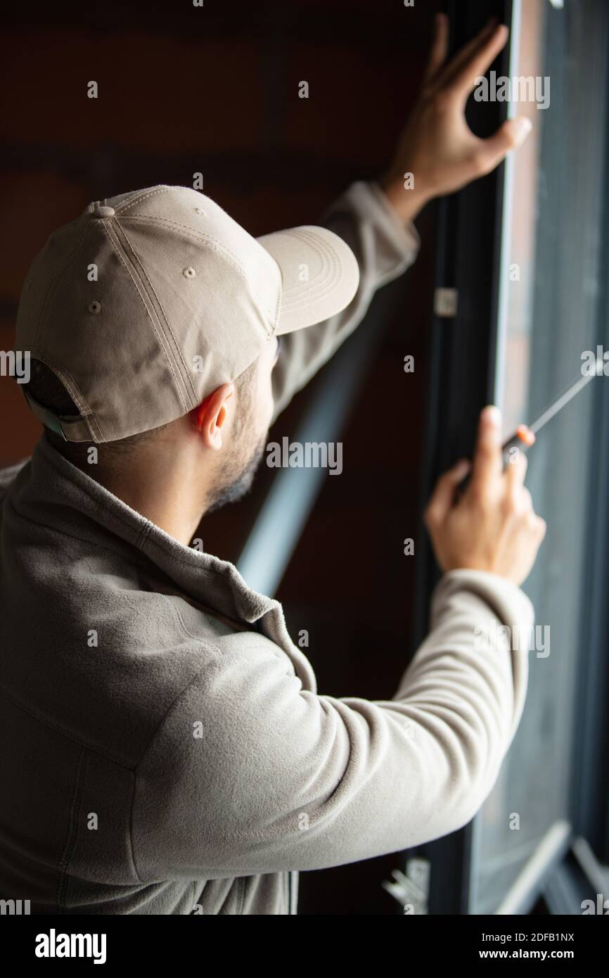 service man installing window with screwdriver Stock Photo - Alamy