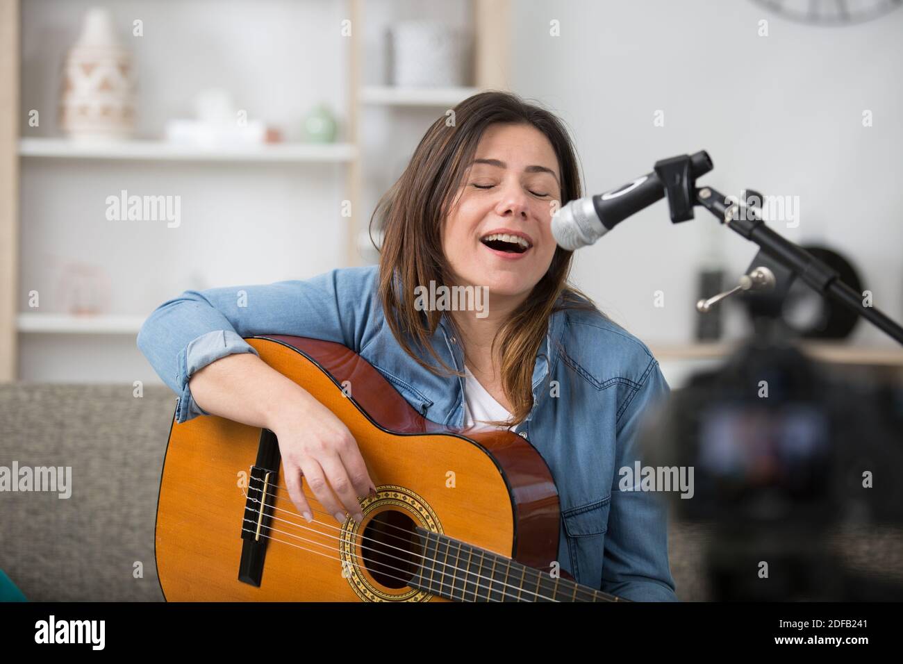 woman playing on acoustic guitar and singing on a microphone Stock ...