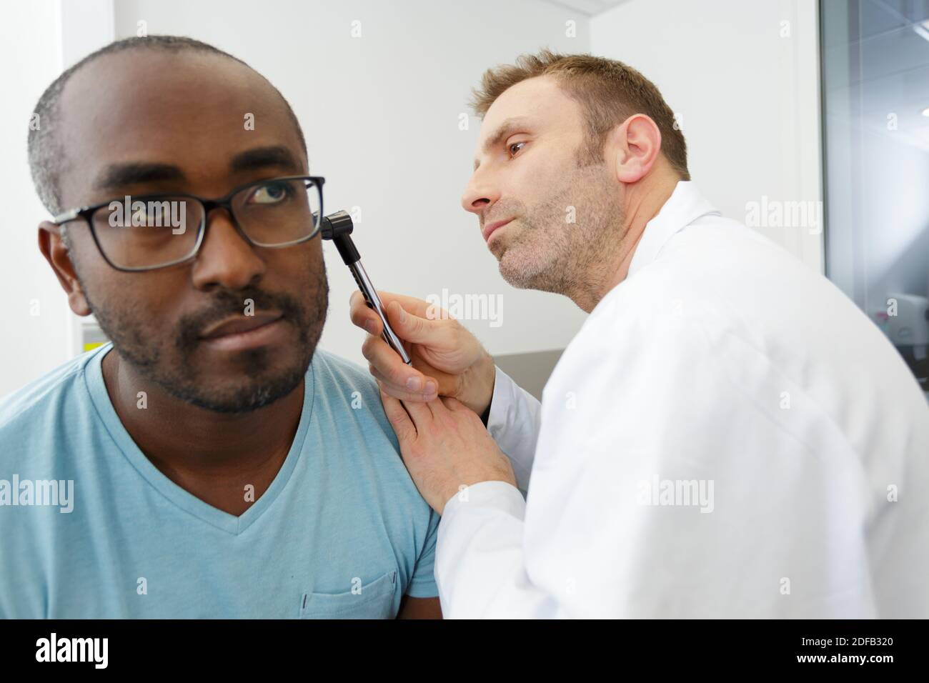 male doctor checking patients ear using otoscope Stock Photo - Alamy