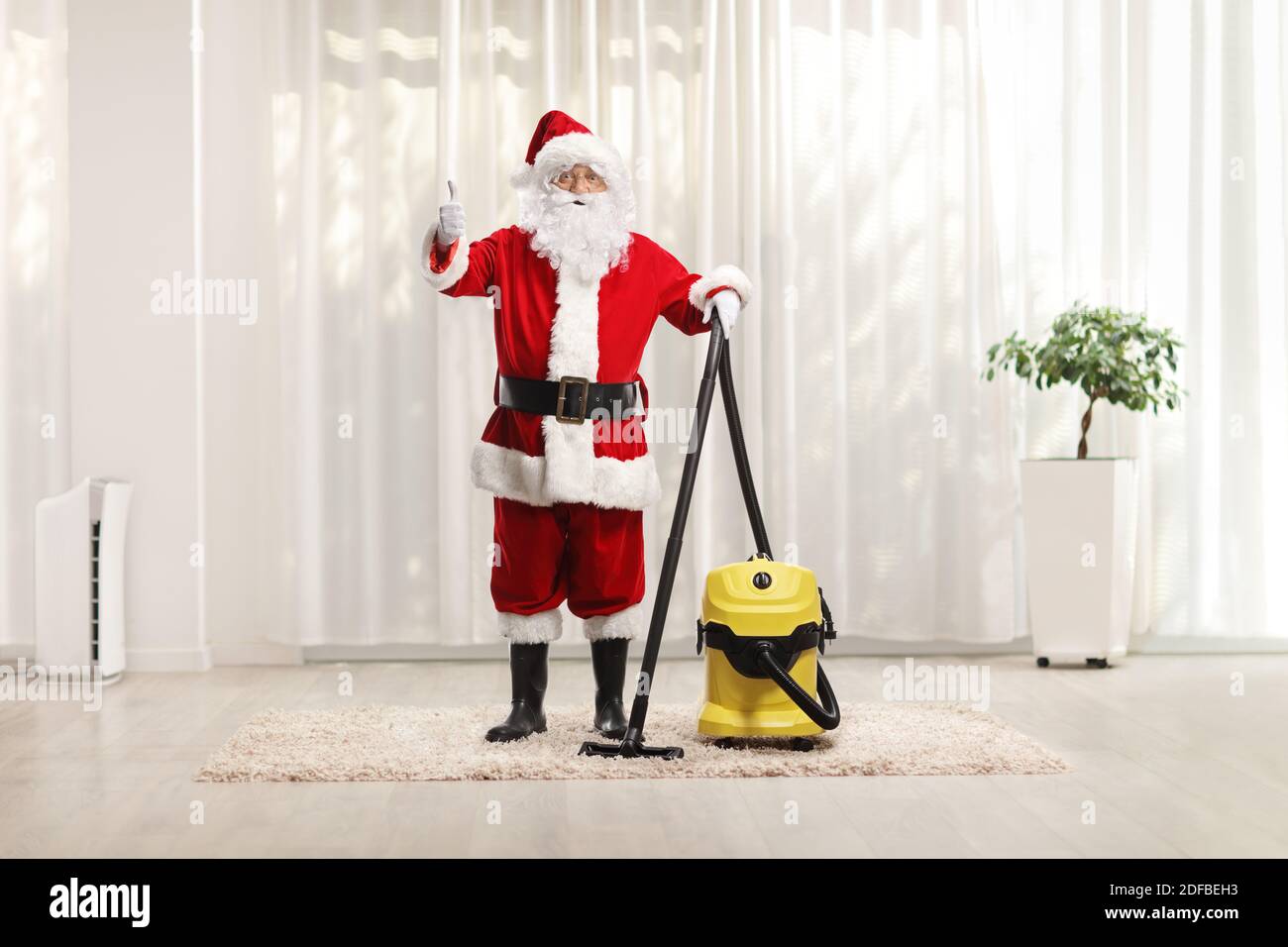 Full length portrait of santa claus at home posing with a vacuum ...