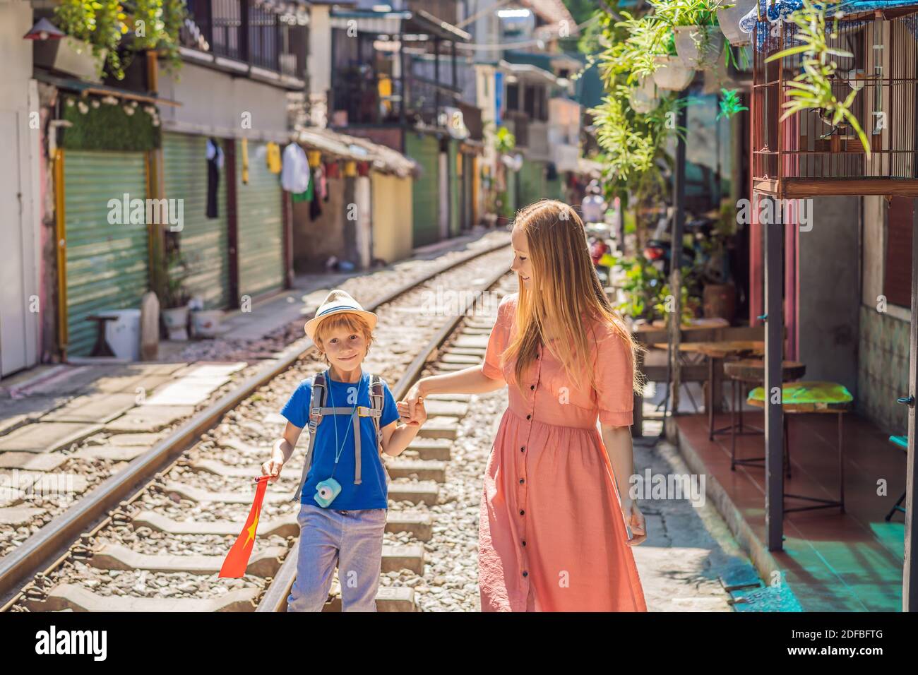 Mother and son travelers walk around railway paths which go through ...
