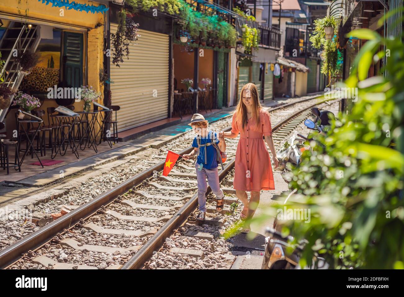 Mother and son travelers walk around railway paths which go through ...
