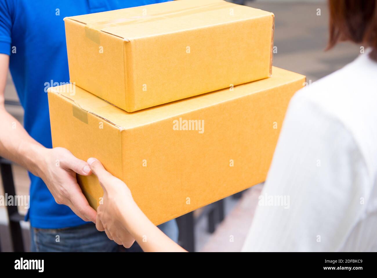 Delivery man in blue uniform handing parcel boxes to a woman - courier ...