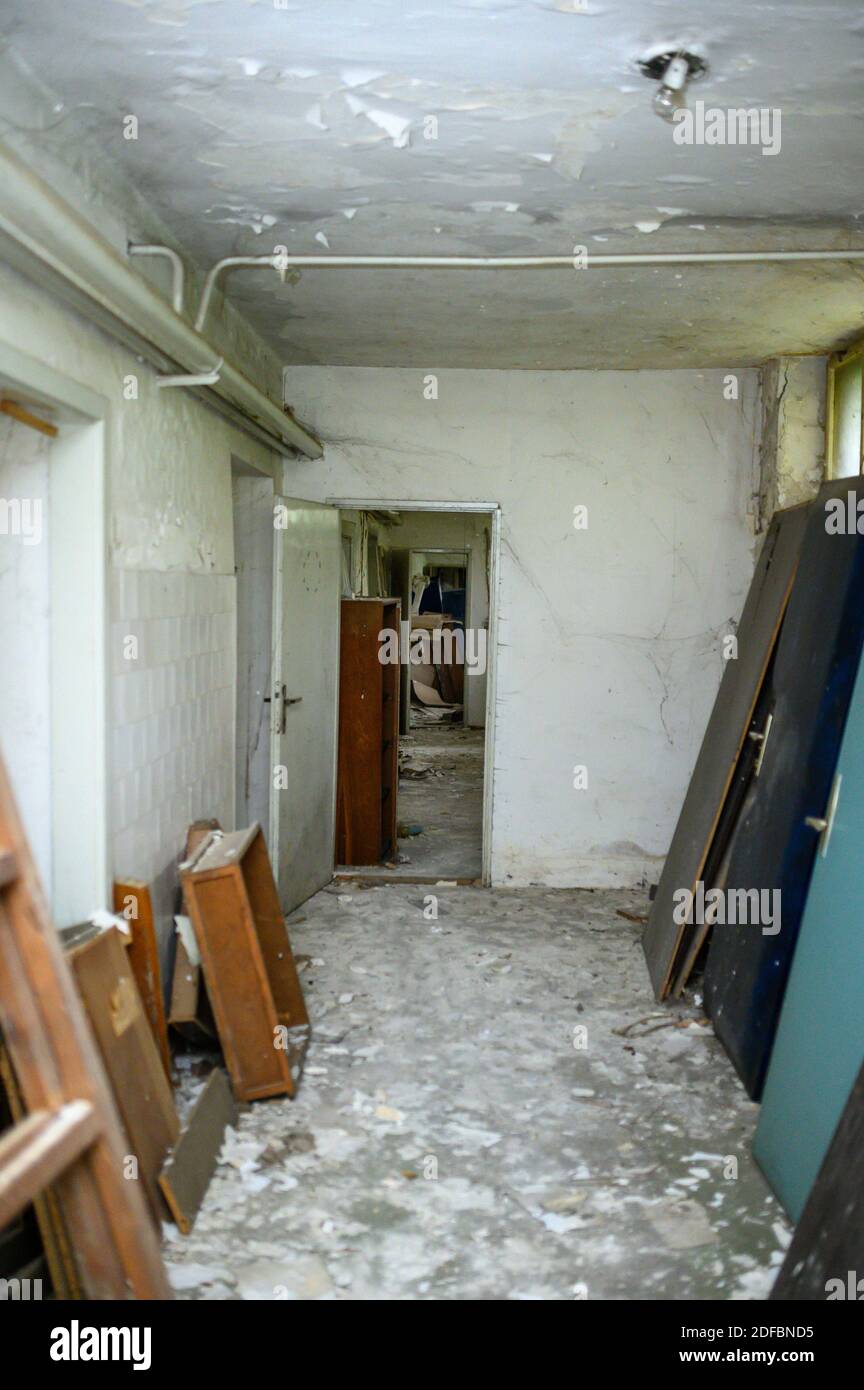 A vertical shot of a damaged corridor with wooden objects and doors ...