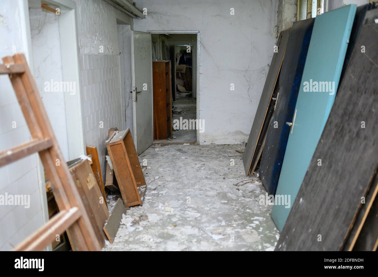 A damaged corridor of an old building with doors and wooden objects on ...