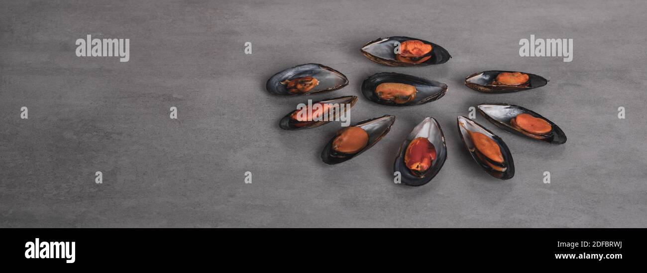 Seafood. The delicious, cooked mussels on a grey stone background ...