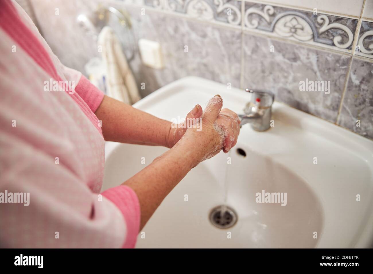 Old woman washing hands with soap in bathroom Stock Photo - Alamy
