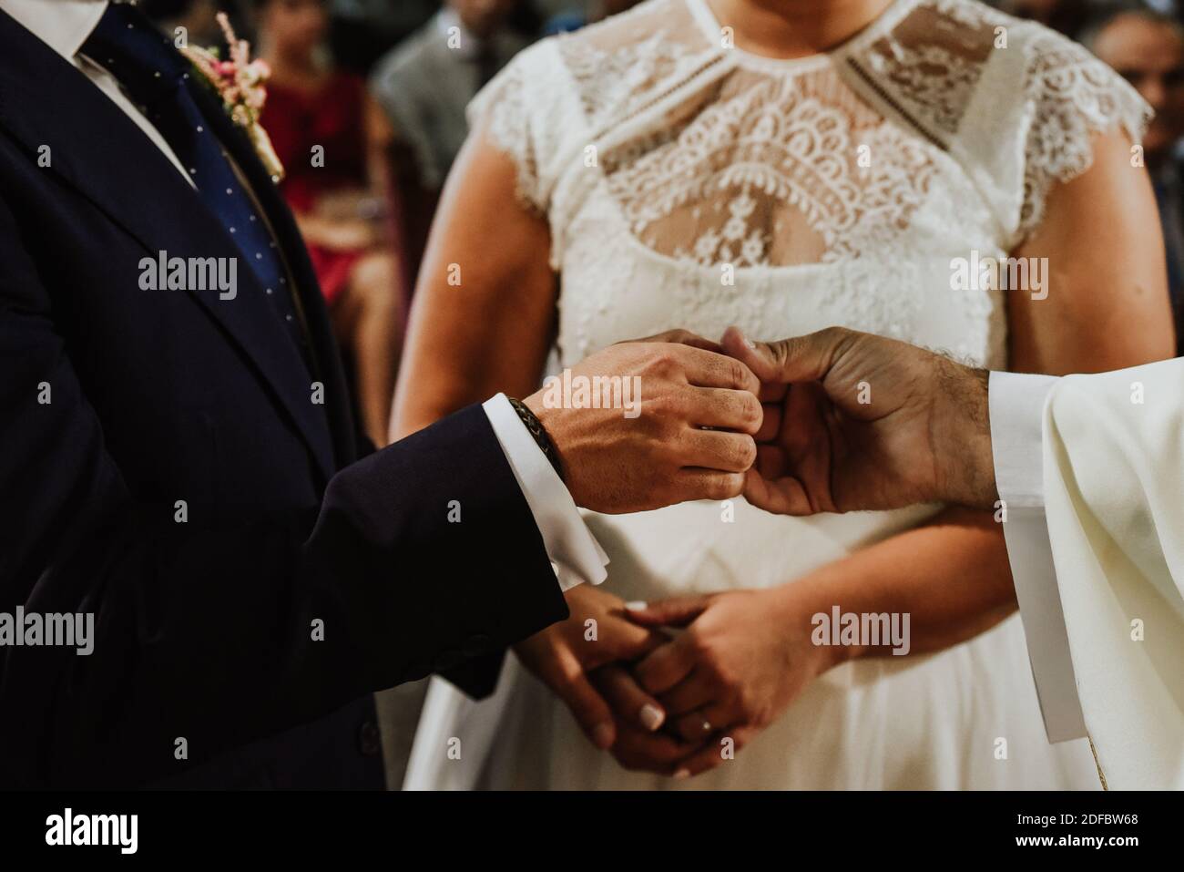 A closeup of the priest giving a ring to the groom during a wedding ...