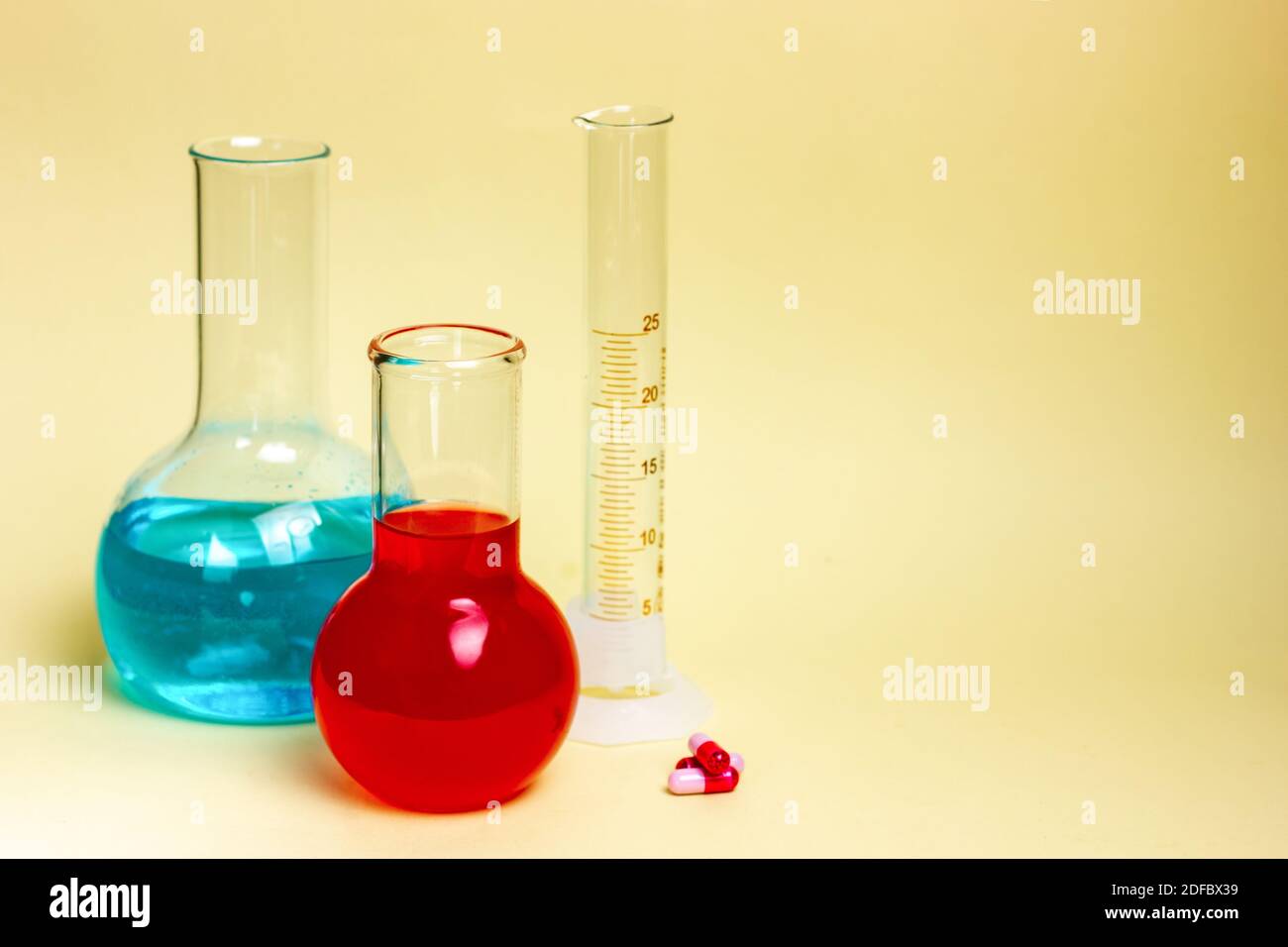 Chemical glassware, flasks and a test tube on a yellow background ...
