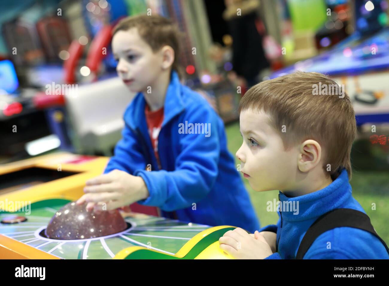 Two children playing arcade game in amusement park Stock Photo - Alamy