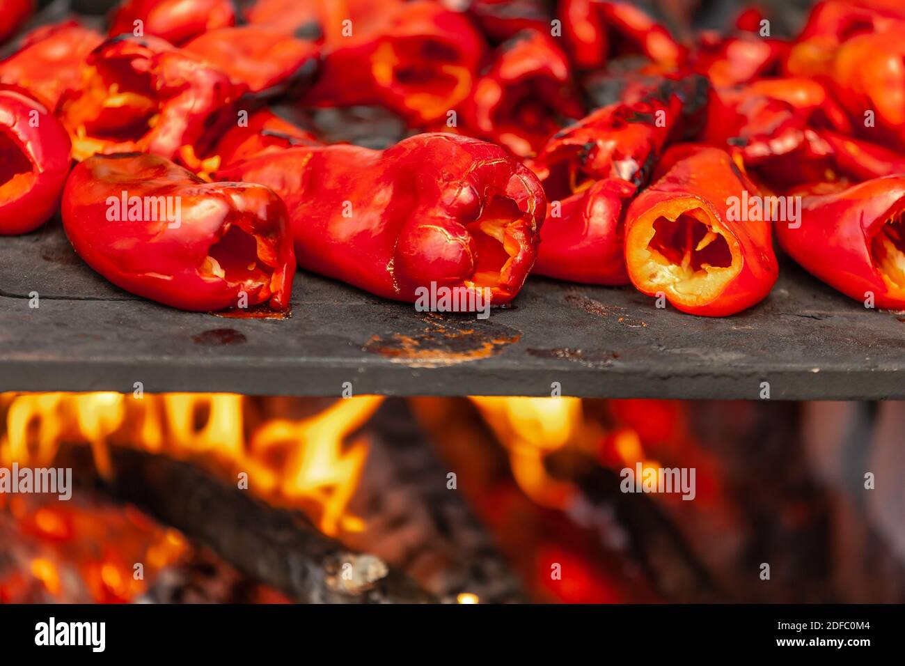 Details with roasted red paprikas on top of an metal stove with wood ...