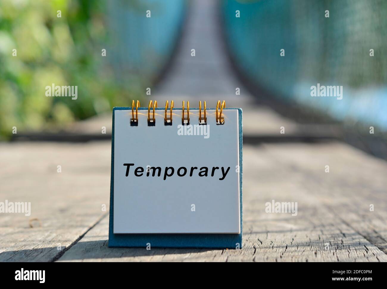 Temporary text written on white note with blurred background of hanging ...