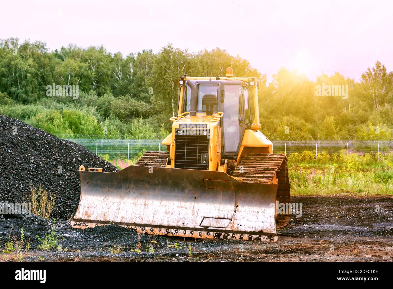 Bulldozer dredges rubble on road construction in the lights of morning ...