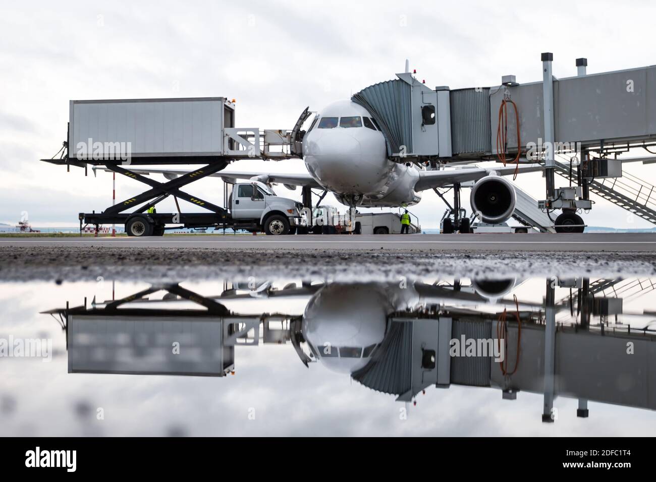 Ground handling of a white passenger aircraft near the air bridge ...