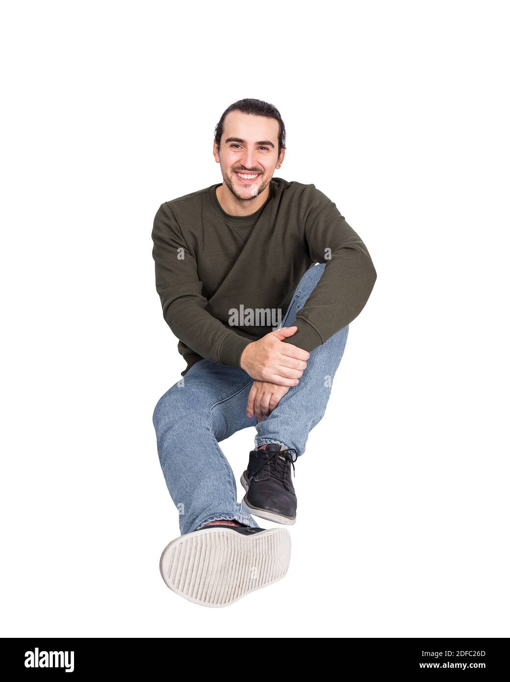 Contented casual young man sitting on the floor smiling to camera ...