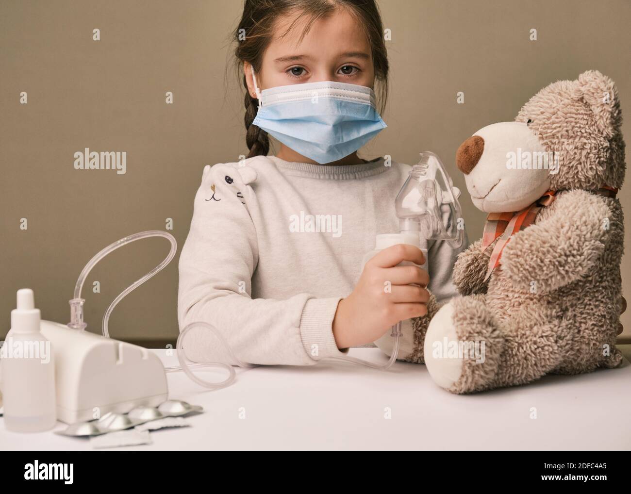 Doctor little girl in mask playing with a toy bear. Child doctor ...