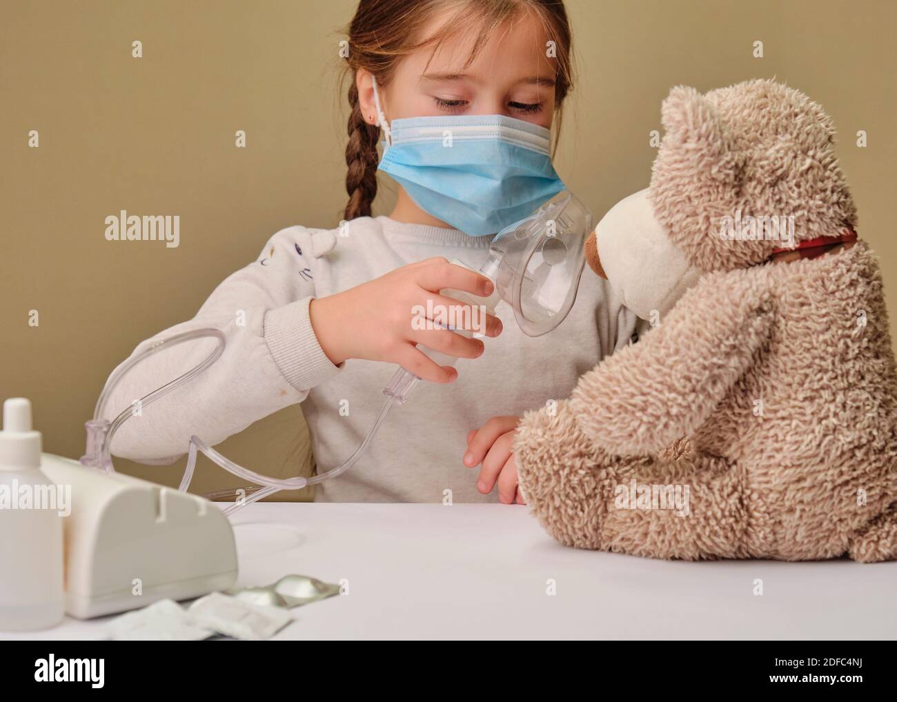 Doctor little girl in mask playing with a toy bear. Child doctor ...