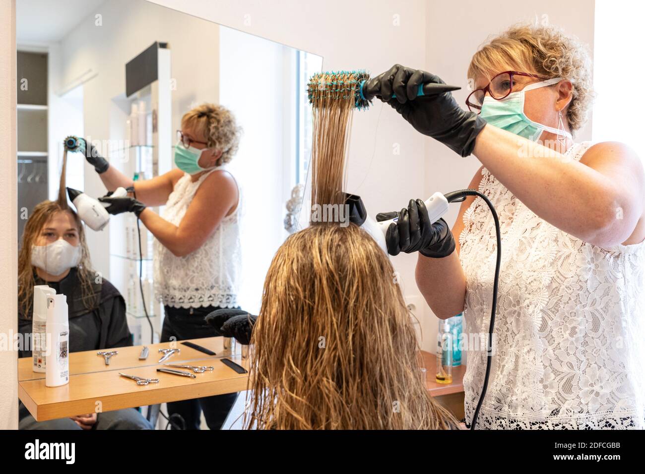 DRYING THE HAIR, HAIRDRESSER WITH HER MASK AND GLOVES DOING A CUSTOMER ...
