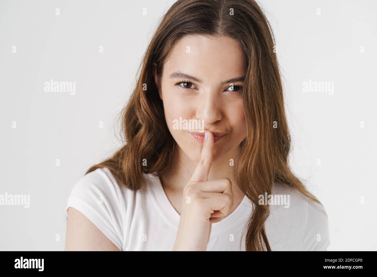 Portrait of a pretty young girl showing silence gesture isolated over ...