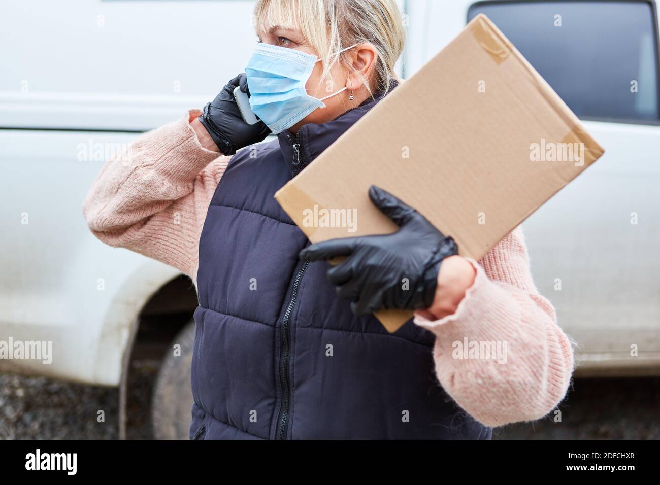 Parcel handler of a delivery service with a face mask calls the ...