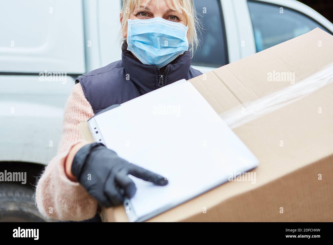 Parcel messenger with face mask asks for confirmation by signature for ...
